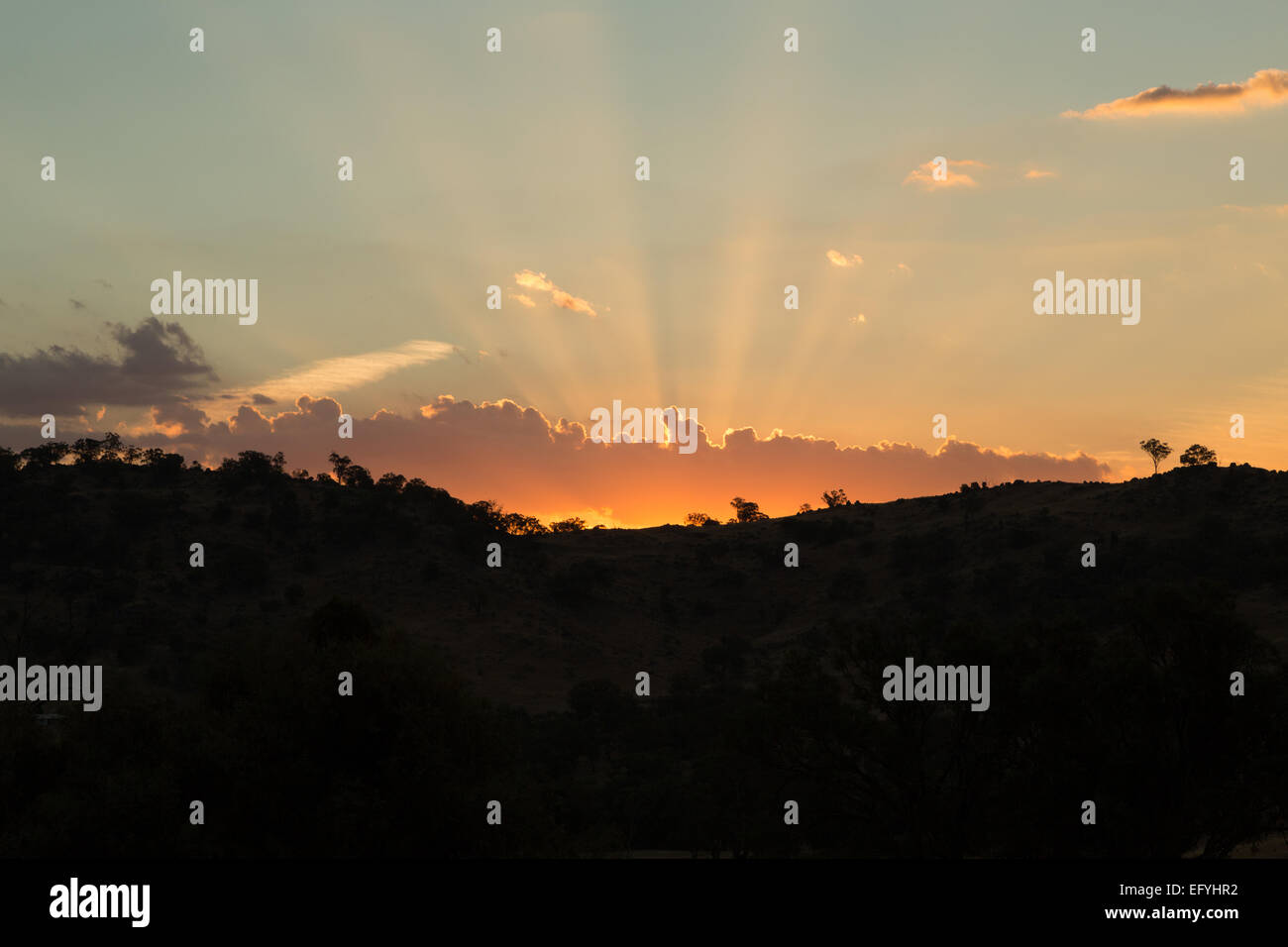 An unedited (RAW) photograph of the sun setting behind some hills. The ...