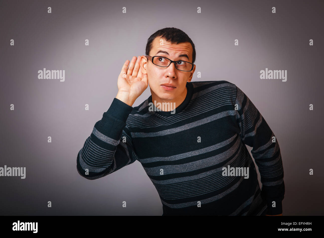 male of European appearance brunet put his hand to his ear on gr Stock ...