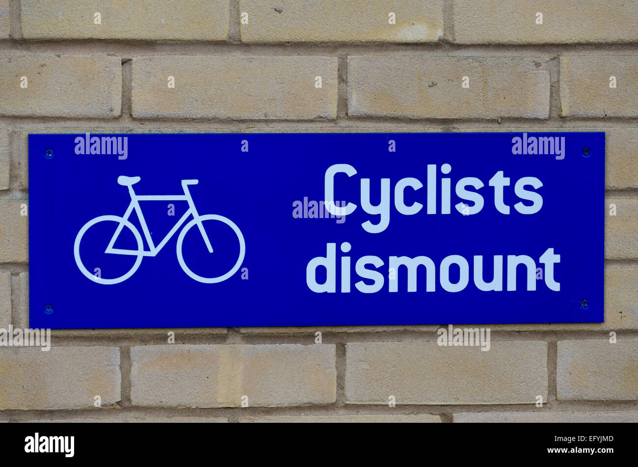 Cyclists dismount sign on brick wall Stock Photo - Alamy