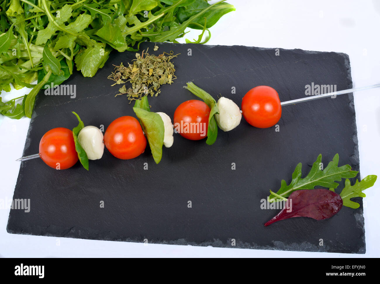 skewer tomatoes on a black slate with salads Stock Photo - Alamy