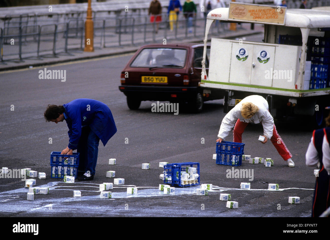 Spilt Milk. Milk delivery man picks up cartons of milk fallen from his ...