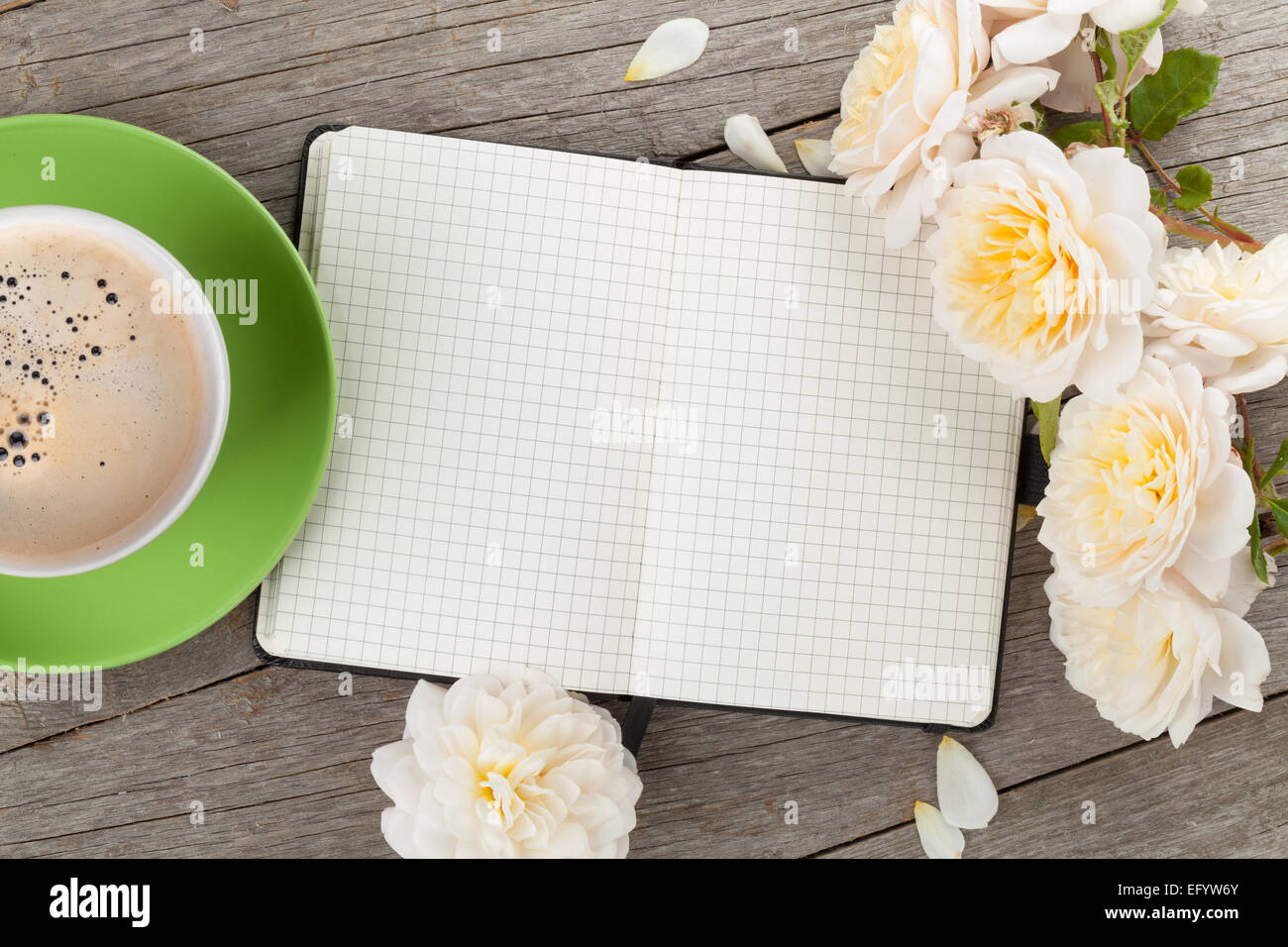 Blank notepad, coffee cup and white rose flowers on wooden table ...