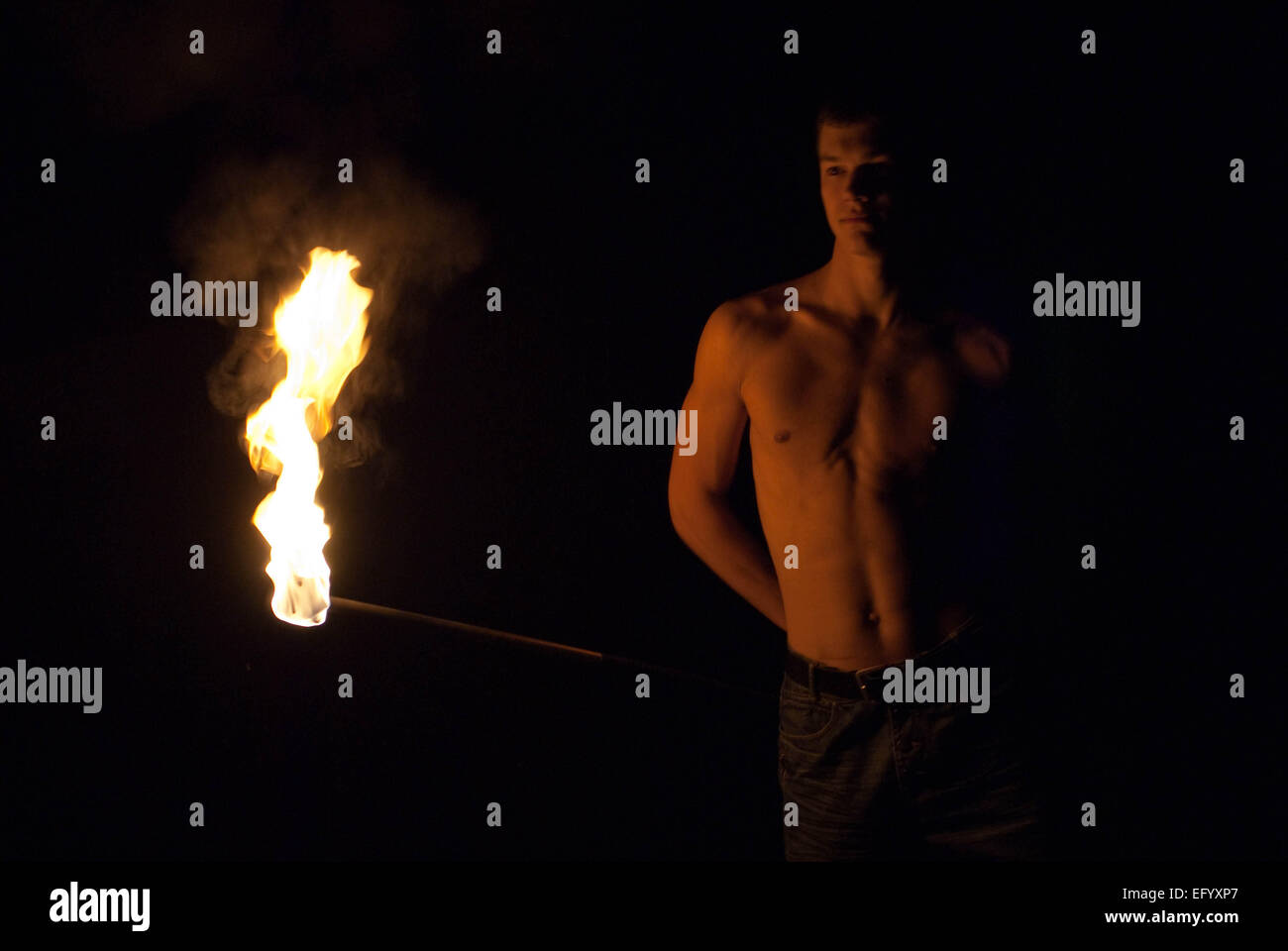fire-eater performance on a street and audience on a dark background ...