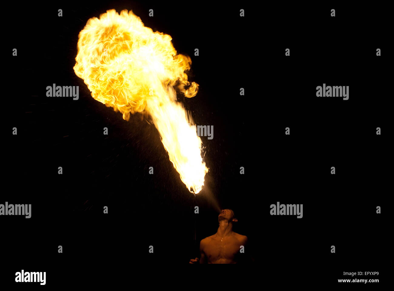 fire-eater performance on a street and audience on a dark background ...