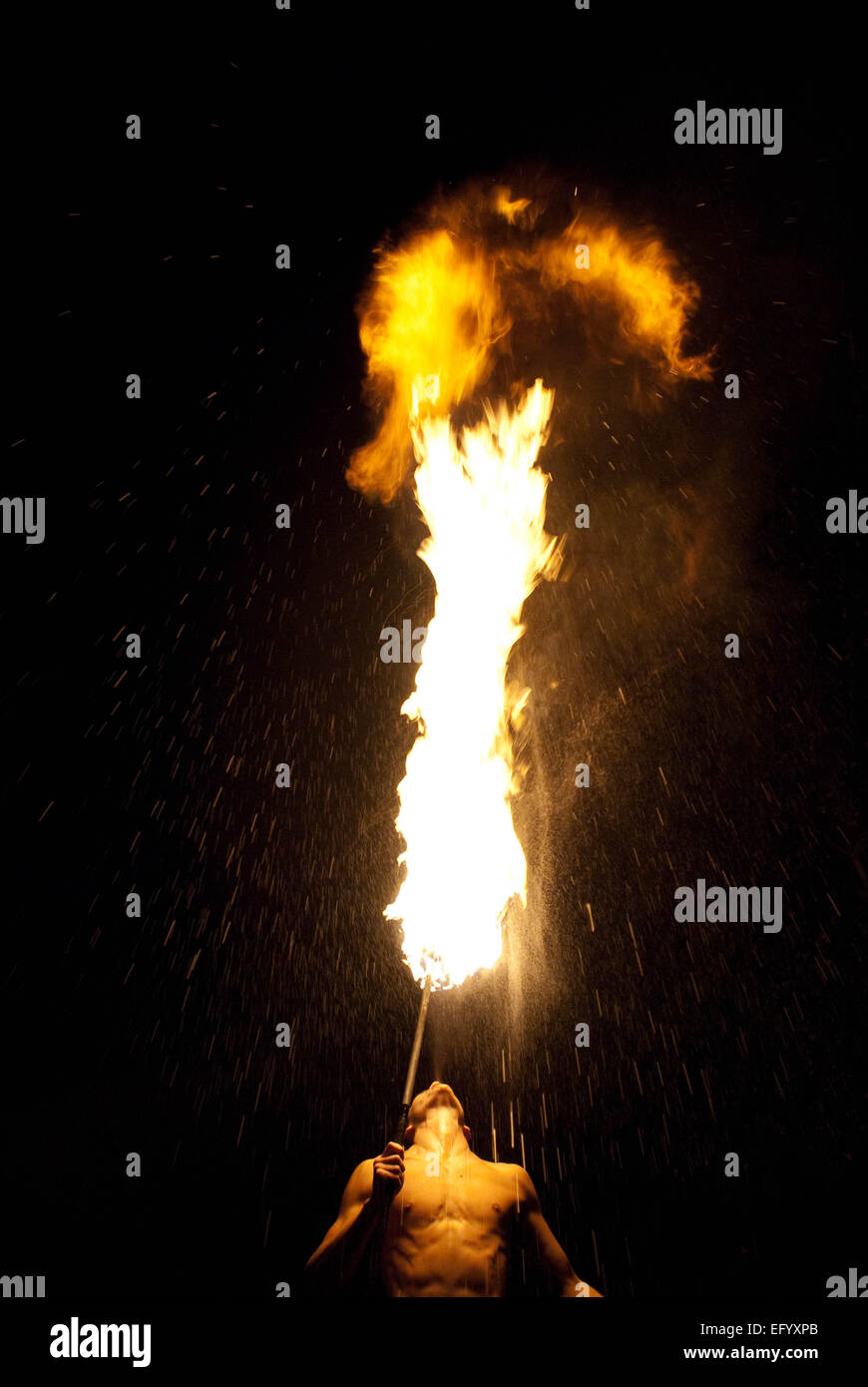 fire-eater performance on a street and audience on a dark background ...