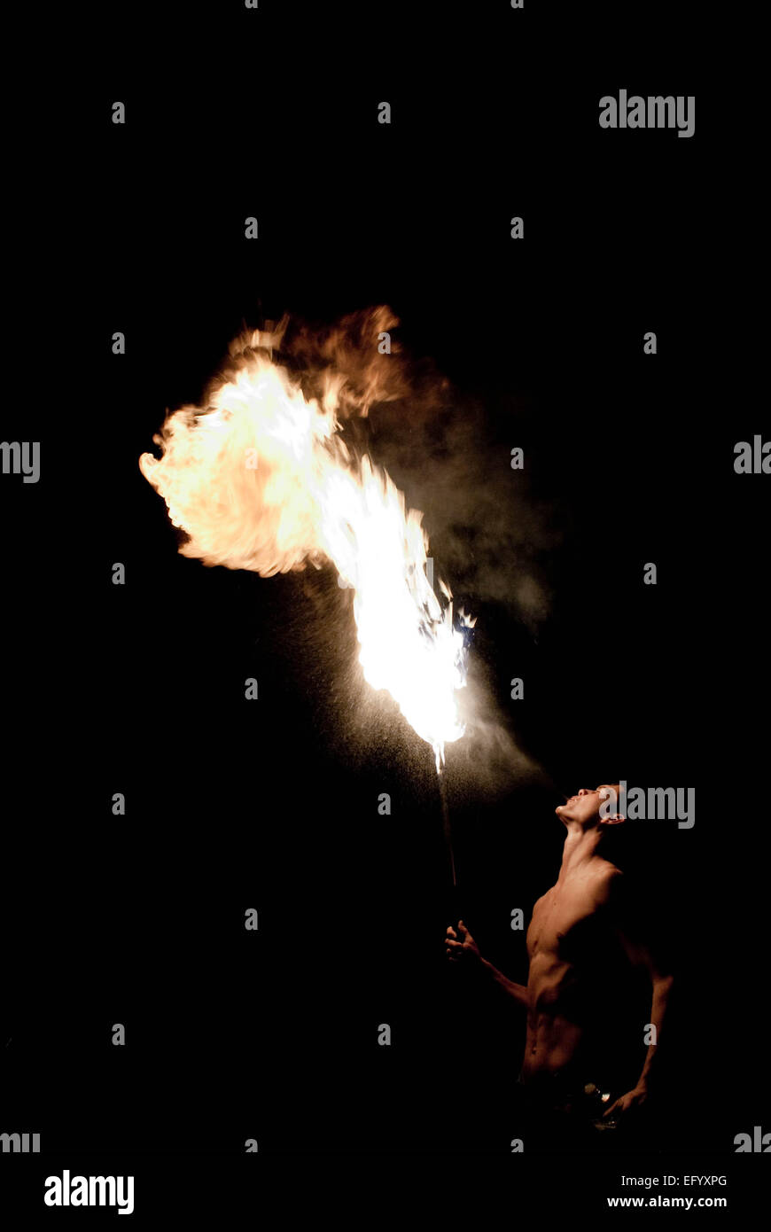 fire-eater performance on a street and audience on a dark background ...