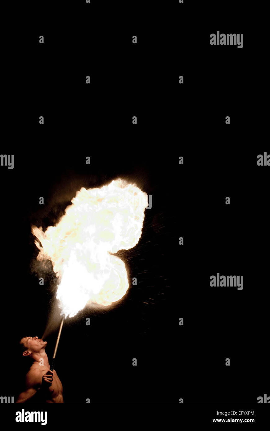 fire-eater performance on a street and audience on a dark background ...