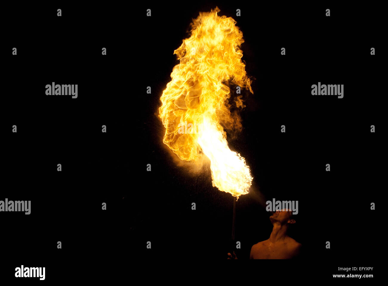 fire-eater performance on a street and audience on a dark background ...