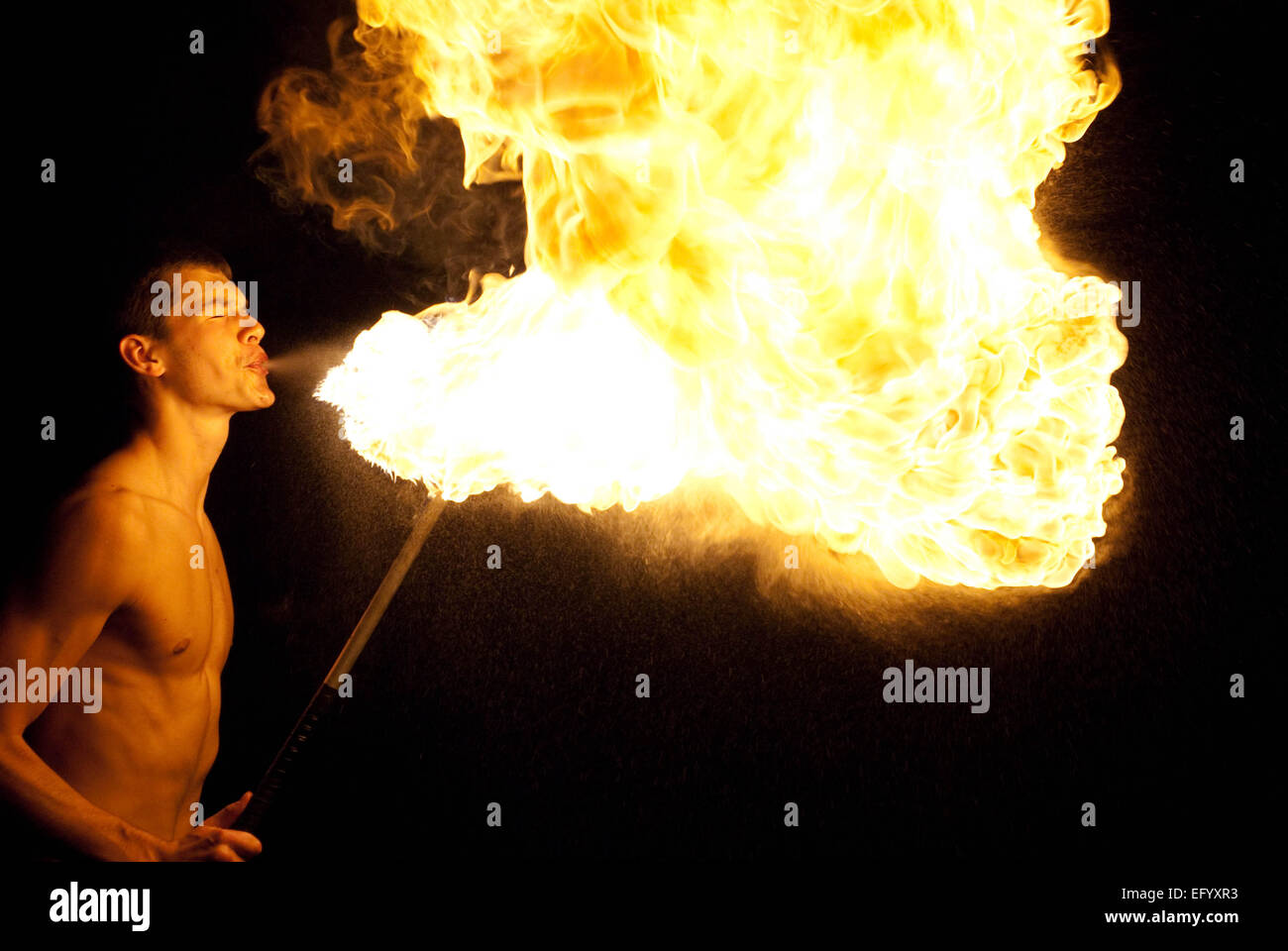 fire-eater performance on a street and audience on a dark background ...