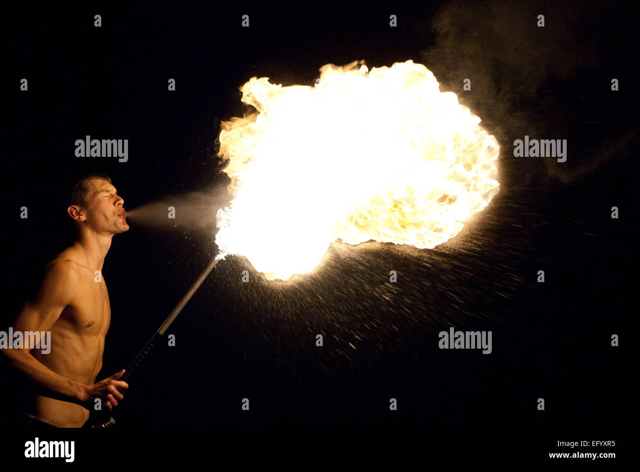 fire-eater performance on a street and audience on a dark background ...