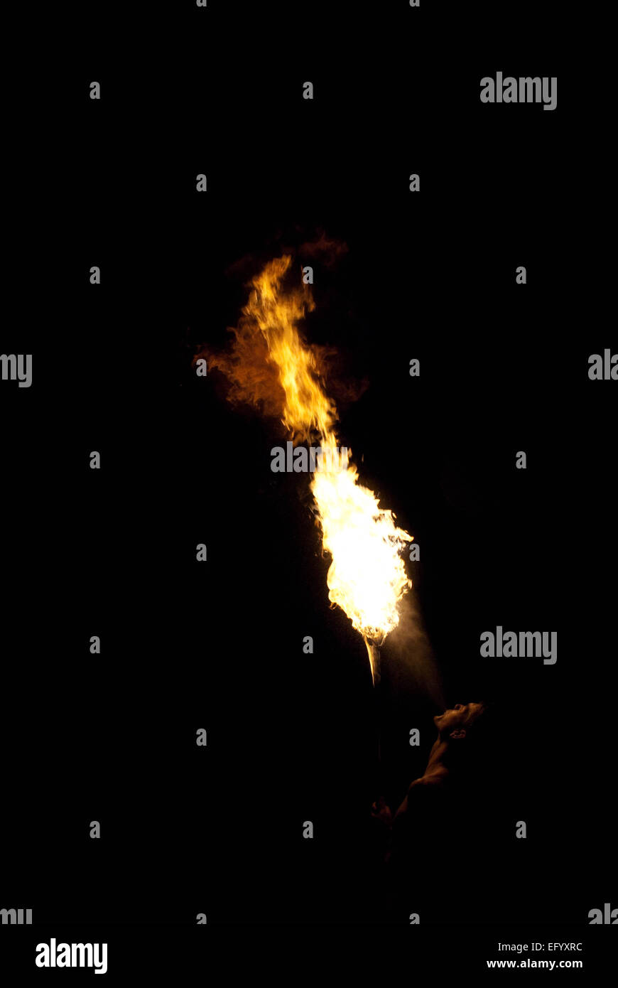 fire-eater performance on a street and audience on a dark background ...