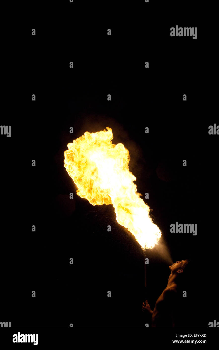 fire-eater performance on a street and audience on a dark background ...