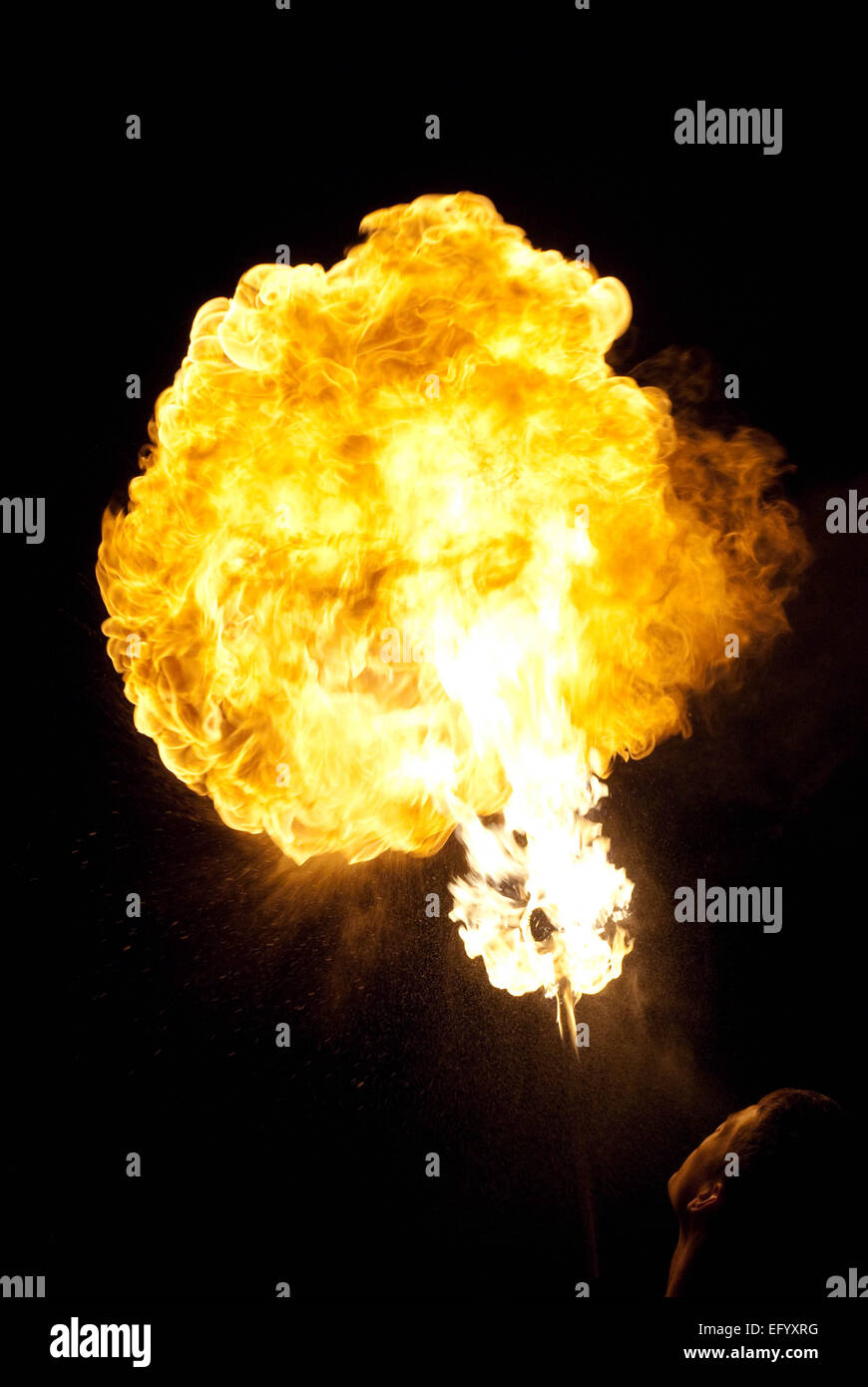 fire-eater performance on a street and audience on a dark background ...
