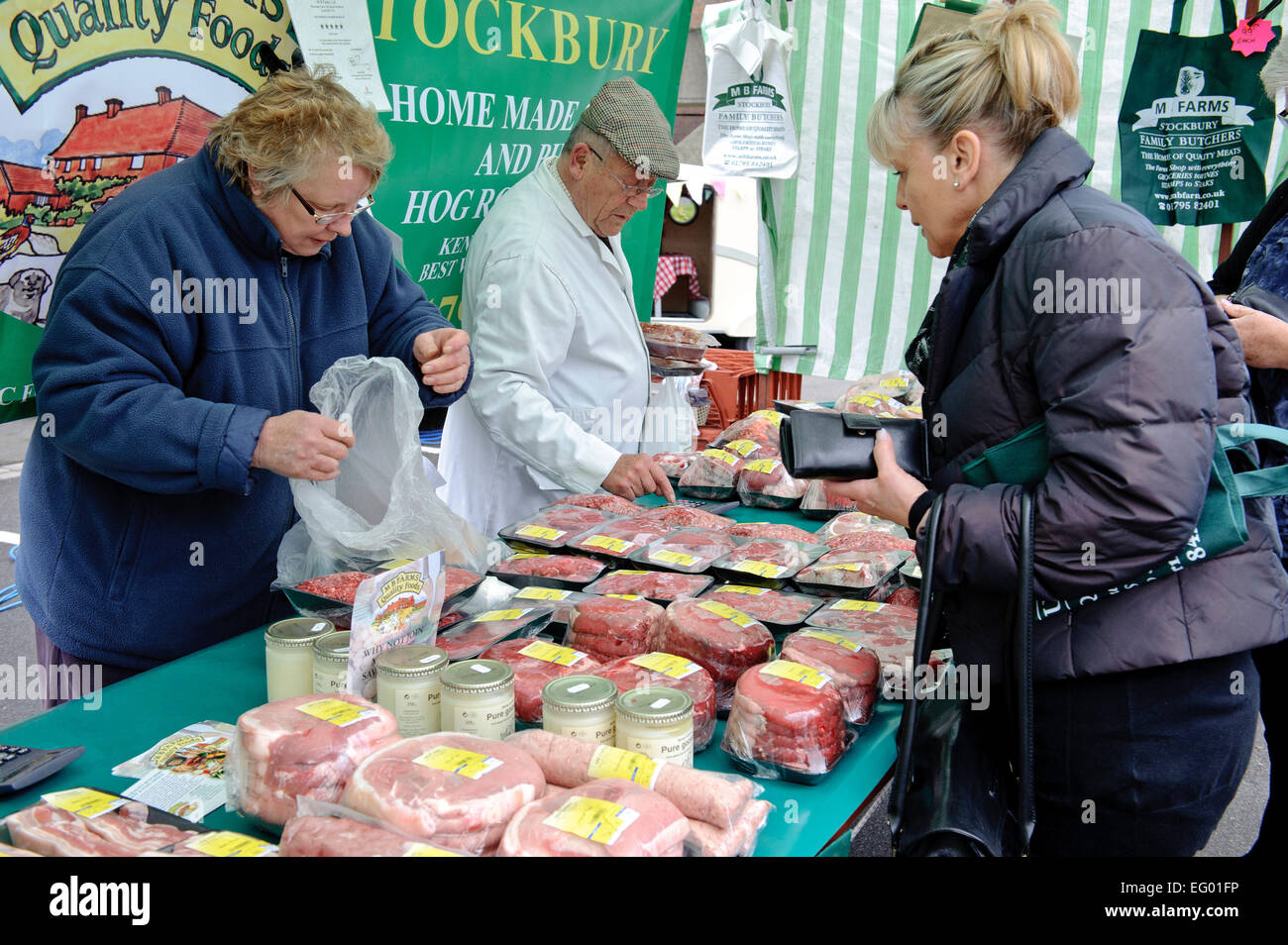 Middle aged woman buying meat product from stall at farmers market Kent ...