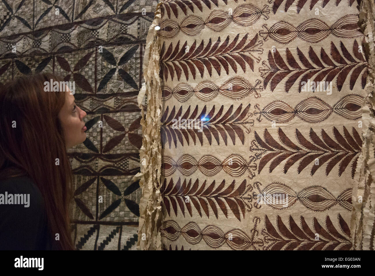 A museum employee looks at a tunic from Niue. The exhibition "Shifting ...