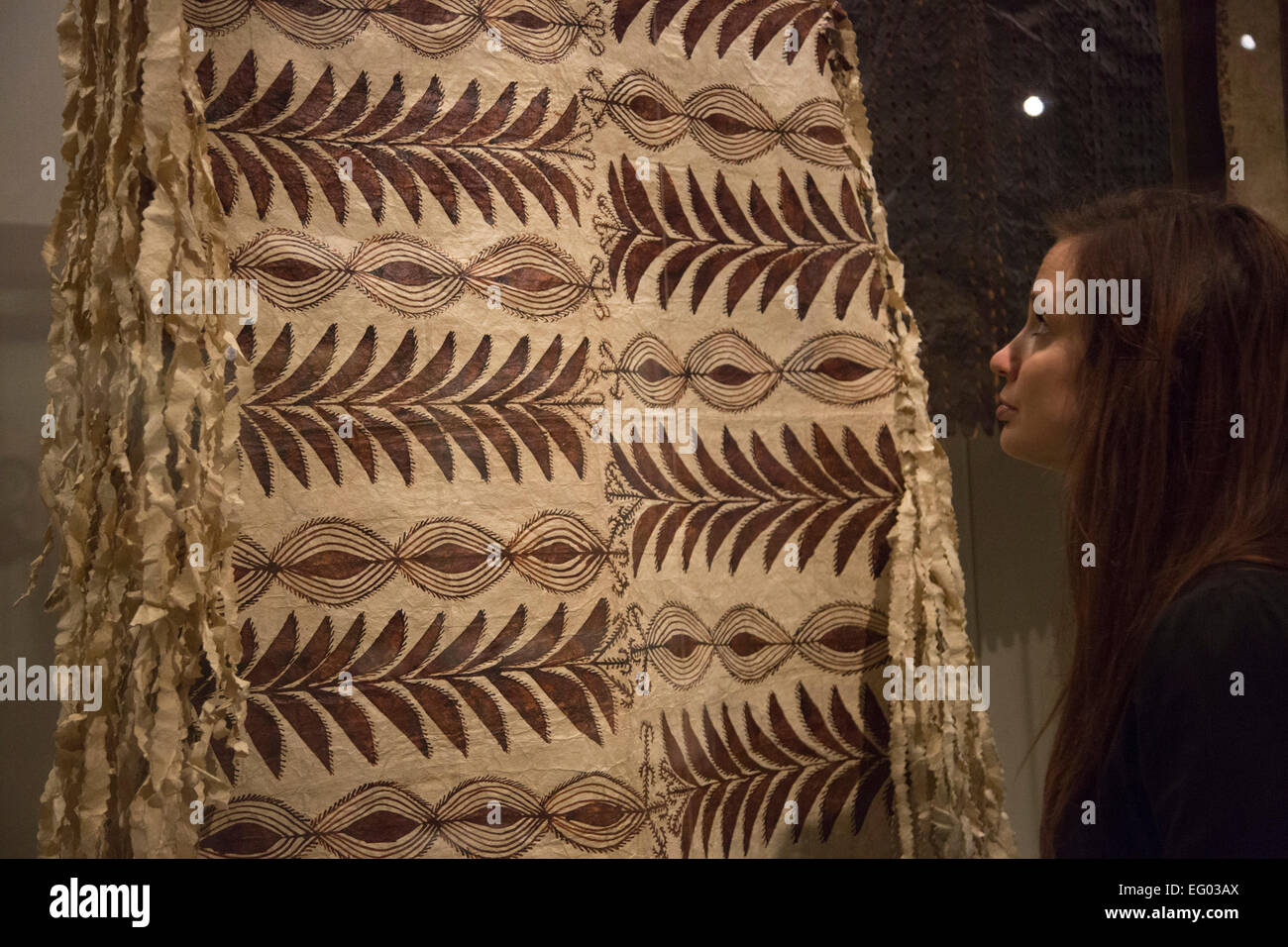 A museum employee looks at a tunic from Niue. The exhibition "Shifting ...
