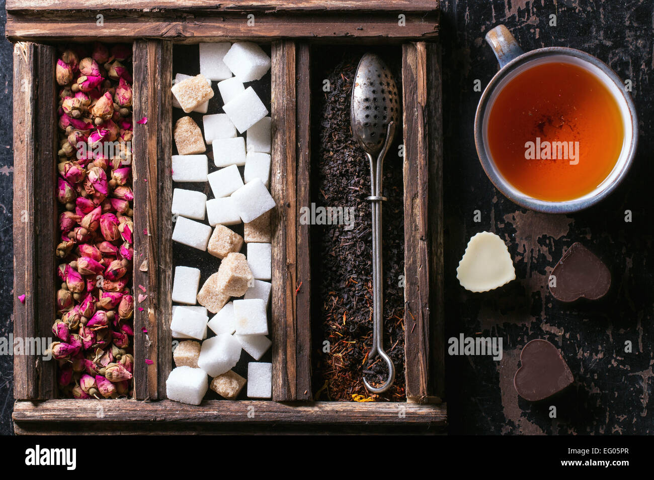Set of dry black tea, tea roses and sugar cubes in wooden box with ...