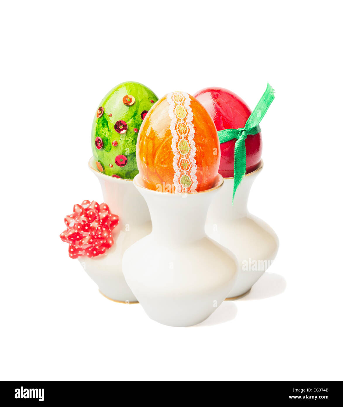 three colored easter eggs in cup with ribbon on white background Stock ...