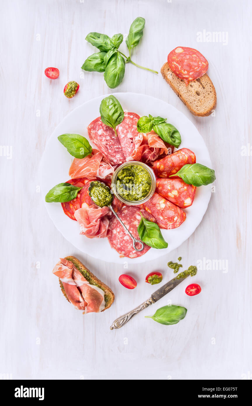 Italian cold meat plate with bread, basil pesto and tomatoes, top view ...