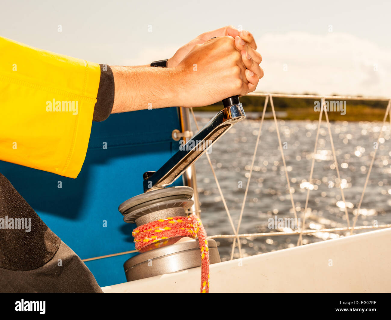 Male hand on winch capstan with rope on sailing boat. Yachting yacht in ...