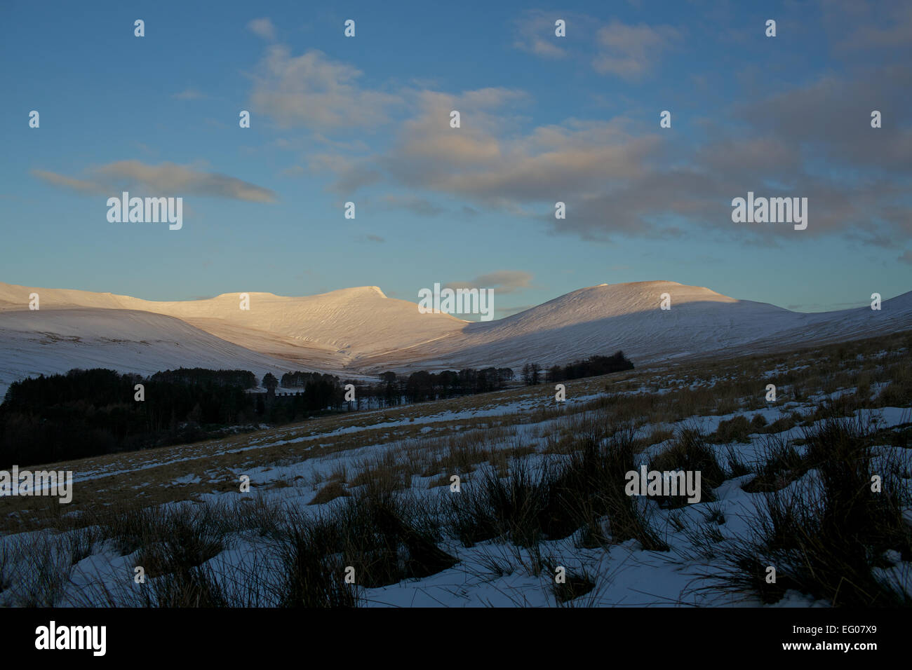 Dawn breaks over the snow covered peaks of Corn Du and Pen Y Fan in the ...