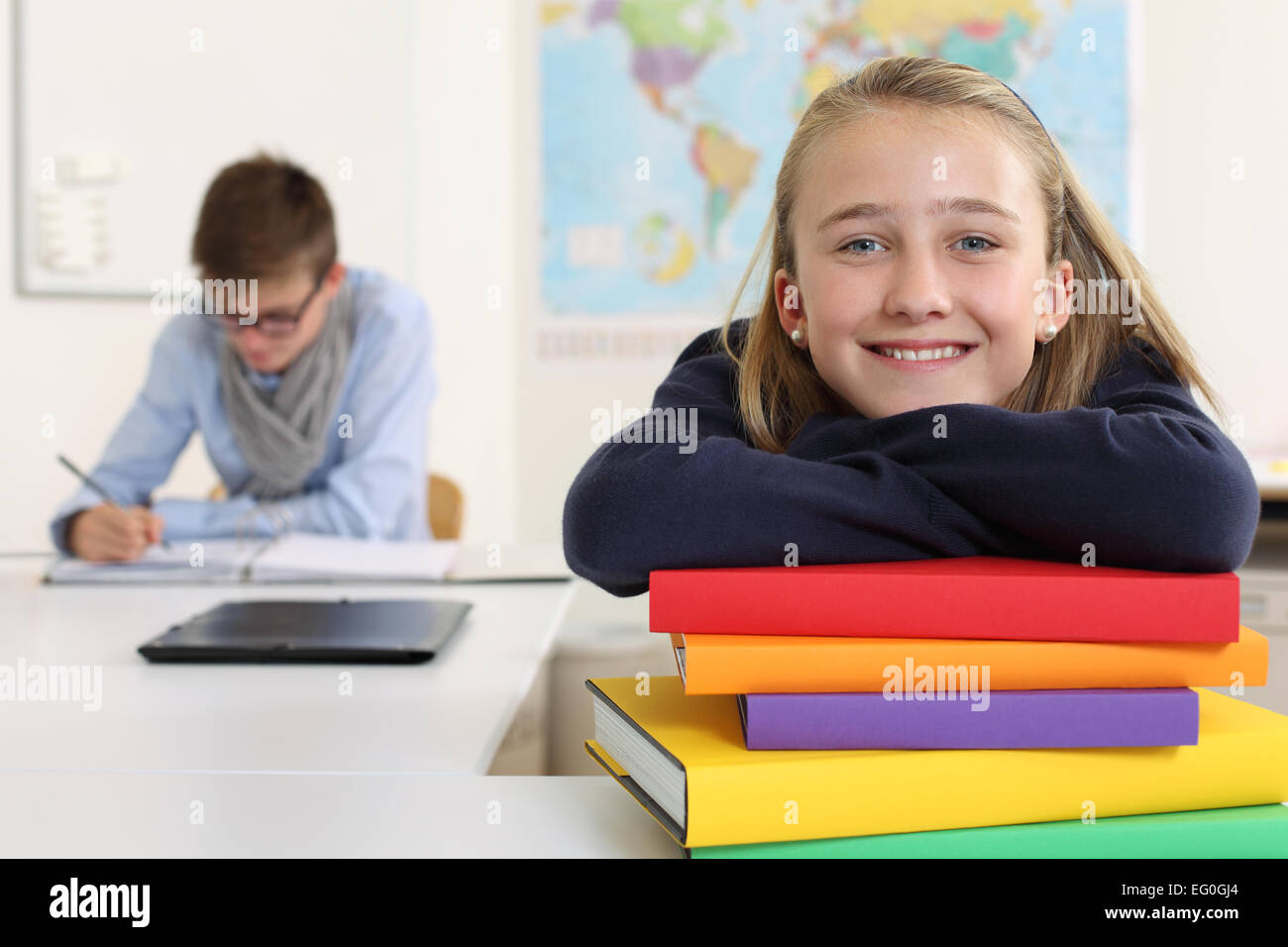Photo of a pretty young girl smiling in her classroom with a male in ...