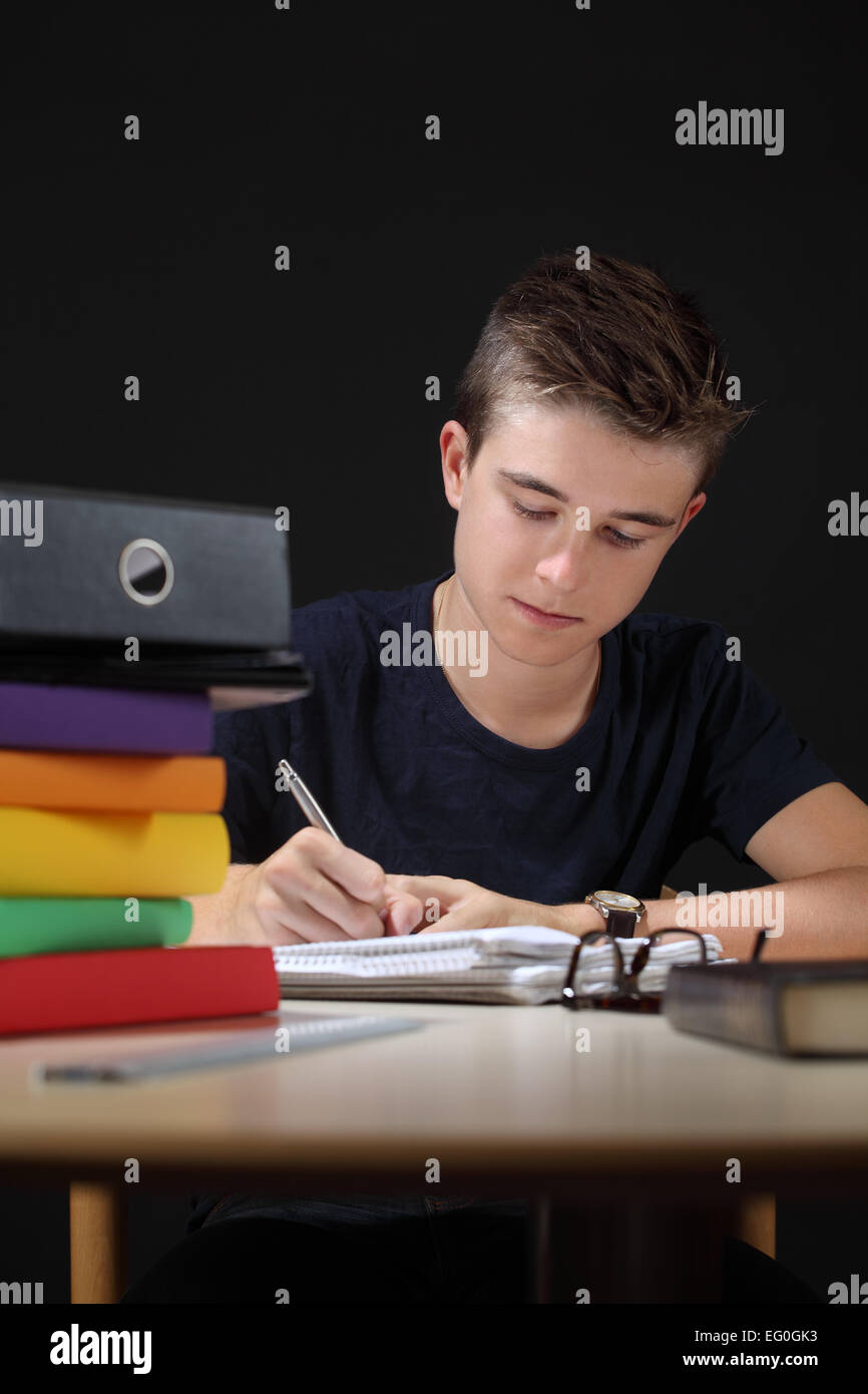 Photo of a young teenager or student writing or doing his homework ...