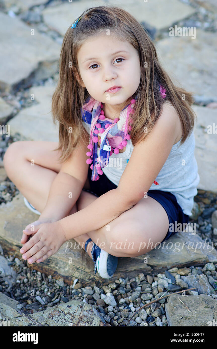 Girl (4-5) sitting on rock path Stock Photo - Alamy