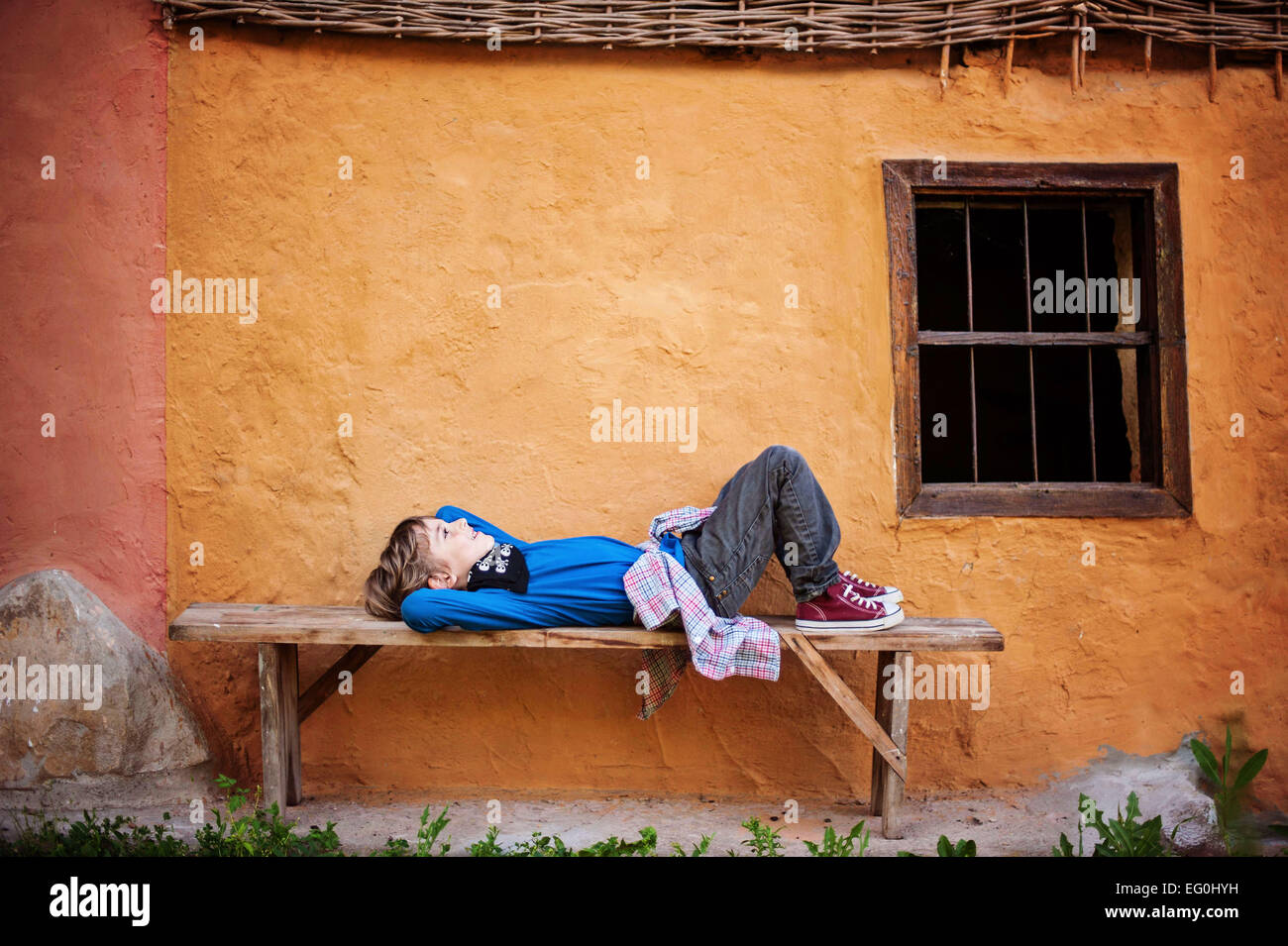 Boy (6-7) laying on bench Stock Photo - Alamy