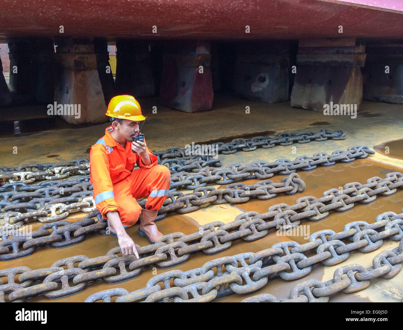 Dock worker in a shipyard talking on a walkie talkie Stock Photo - Alamy