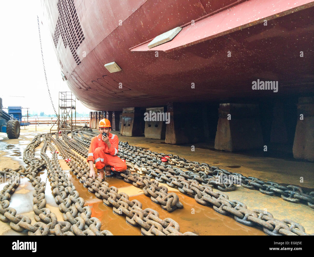Dock worker in a shipyard talking on a walkie talkie Stock Photo - Alamy