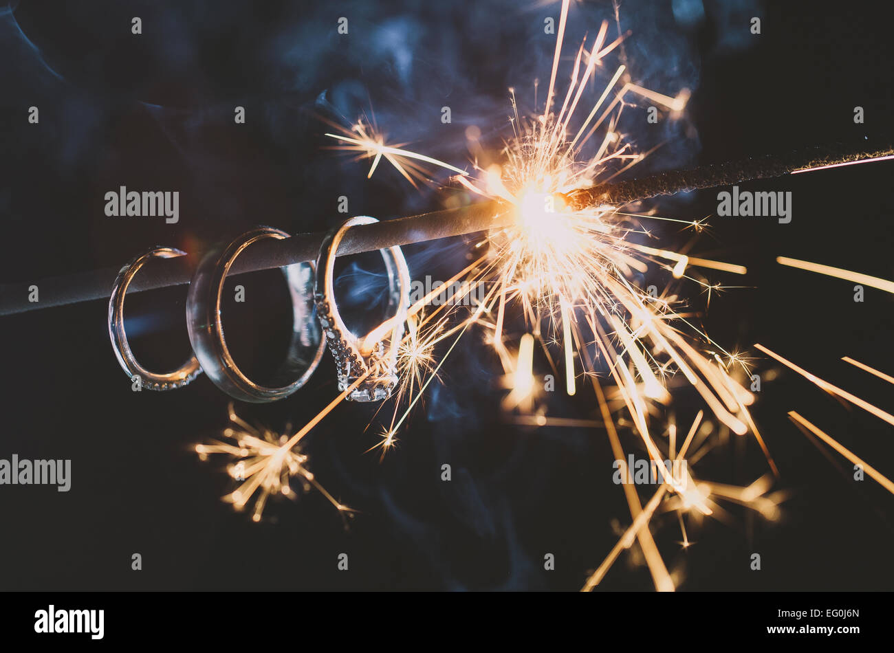 Wedding Rings hang on a sparkler as it burns down illuminating the ...