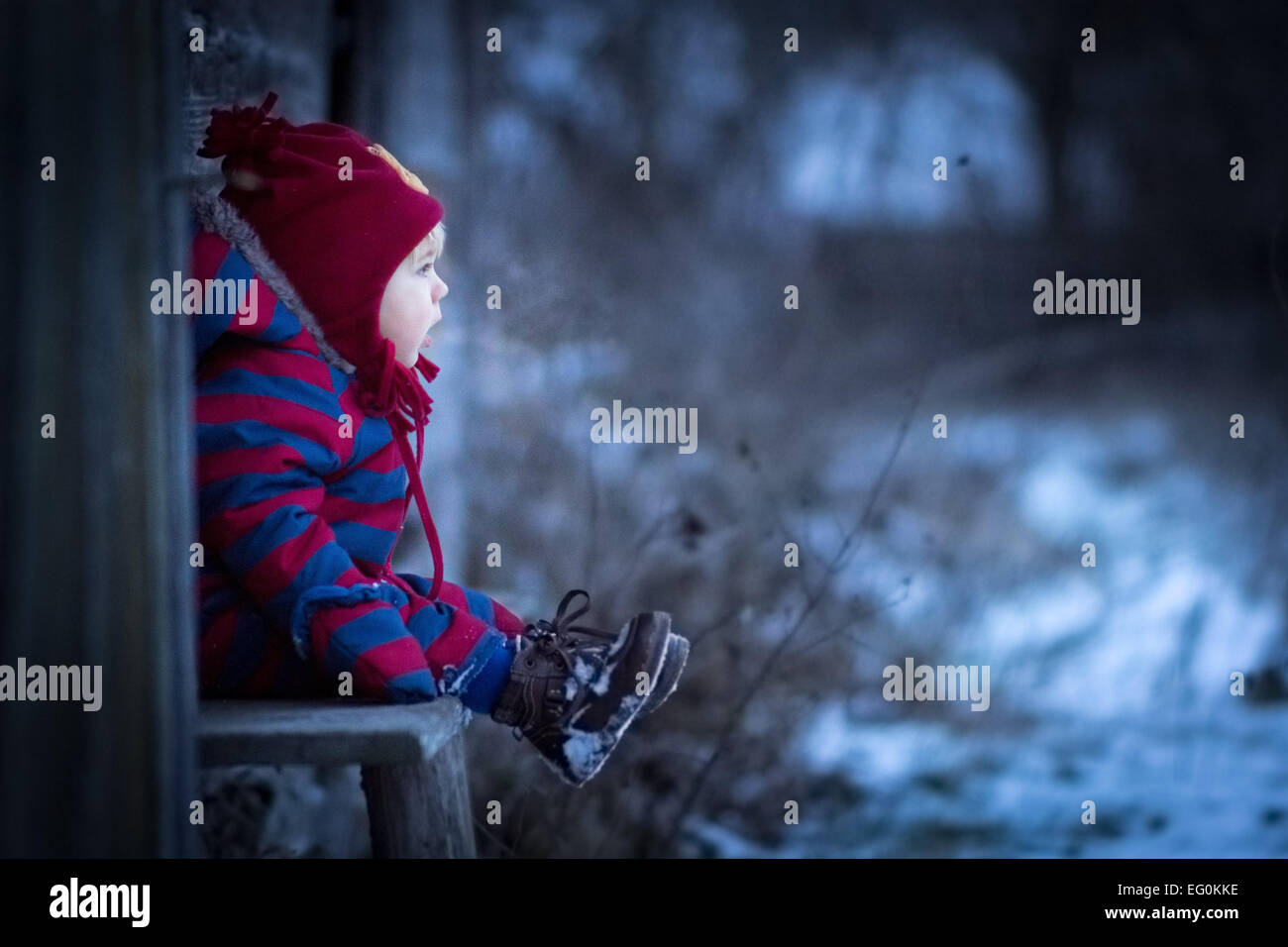 Young boy sitting on bench outside Stock Photo - Alamy