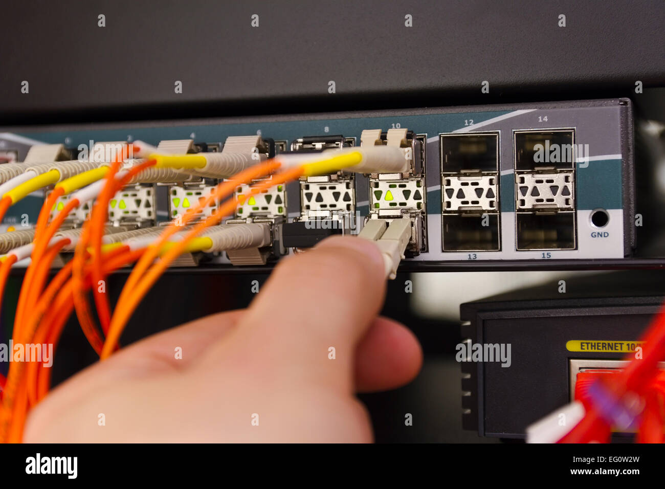 Insert a fiber cable into a switch in datacenter Stock Photo - Alamy