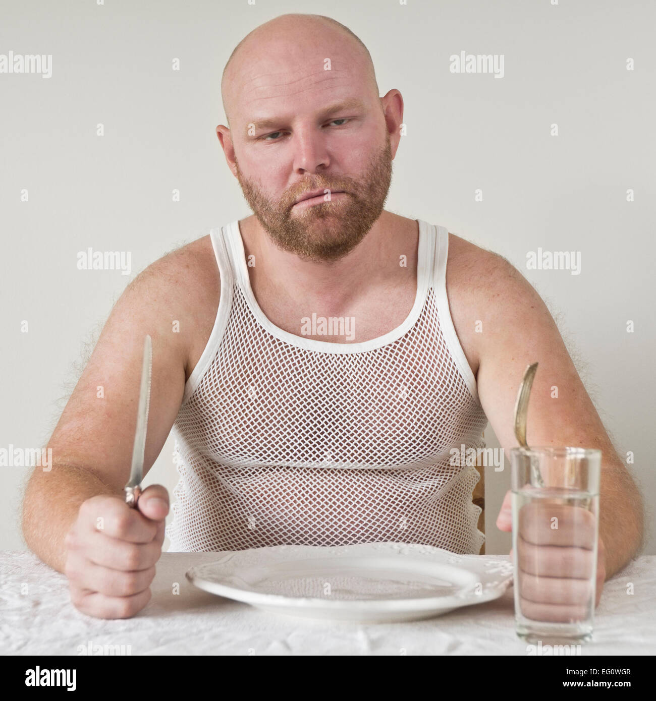 Hungry man with no food on his plate. Perphas on a diet Stock Photo - Alamy