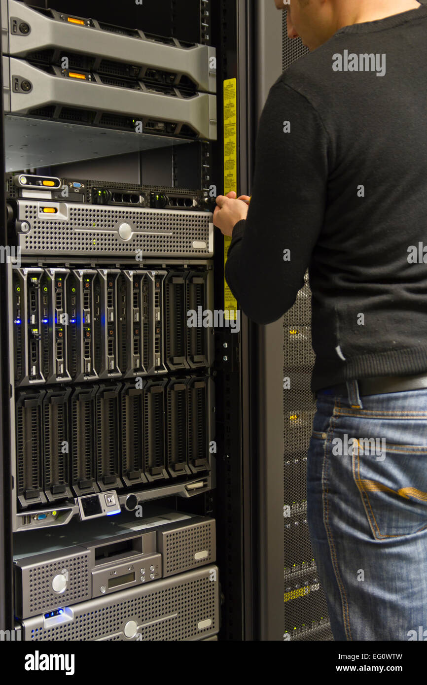 A working IT engineer / technician installing a server in a rack at the ...