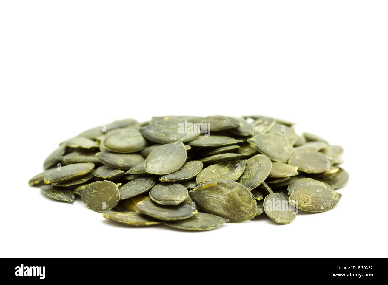Side view of raw organic pumkin seeds / kernels on white background ...