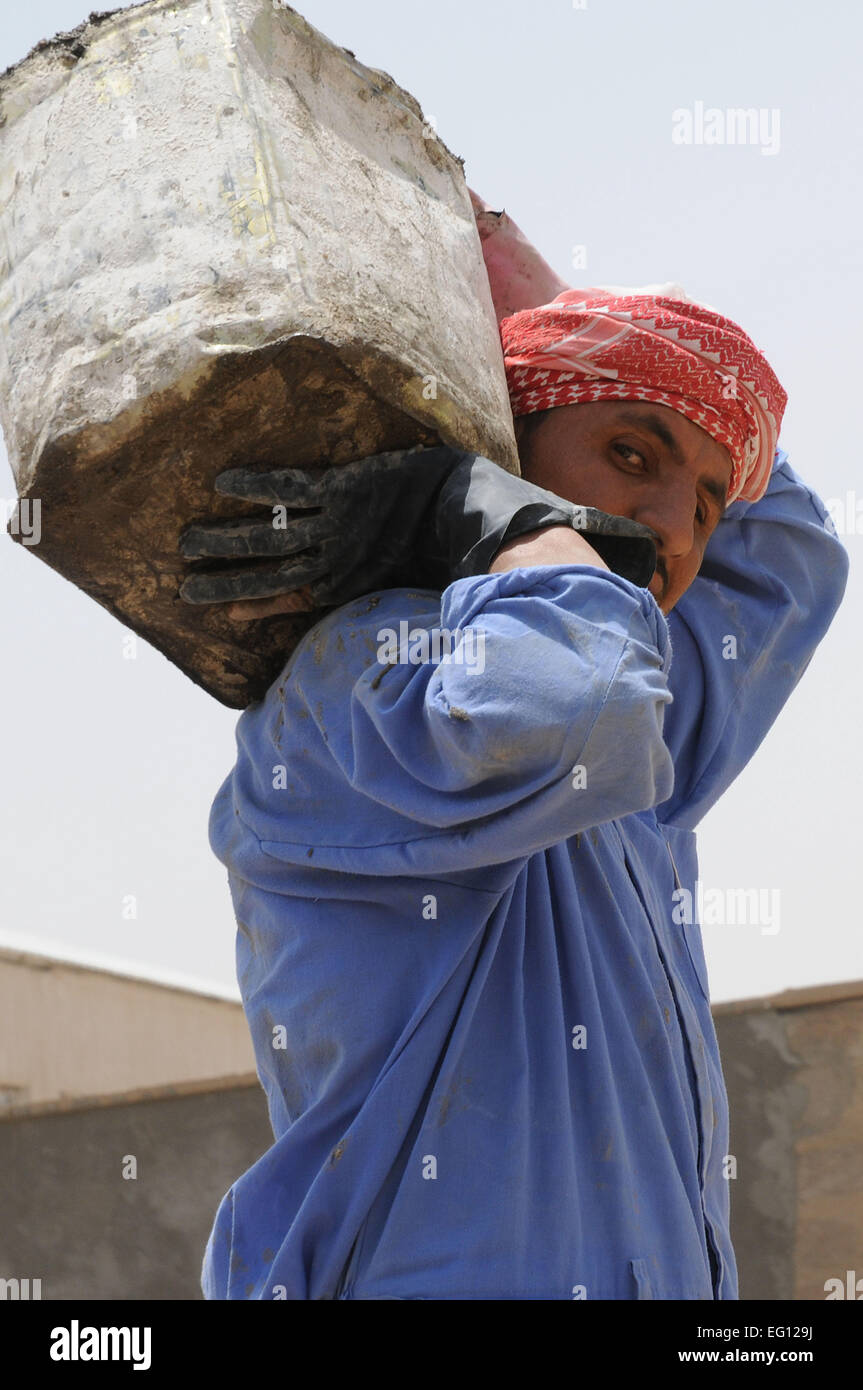 An Iraqi worker carries cement to be used for a brick wall as part of ...