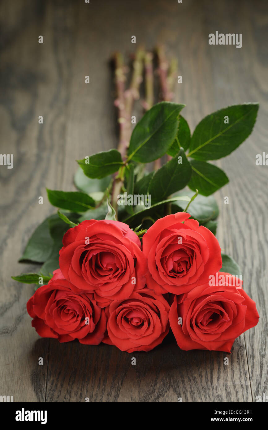 five red roses on old oak table Stock Photo - Alamy