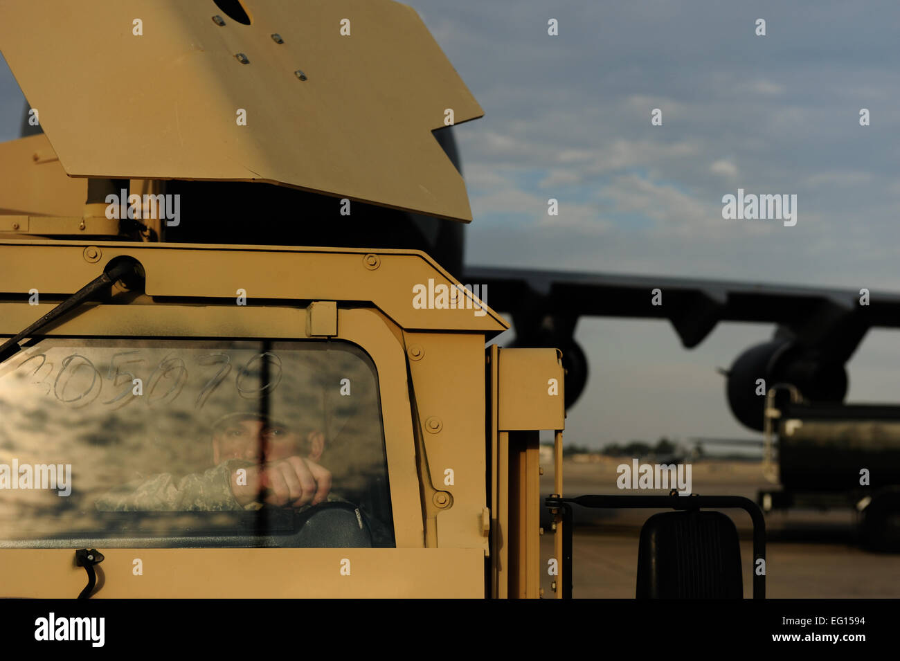 A U.S. Army Soldier waits in a HUMVEE while a U.S.Air Force C-17 ...