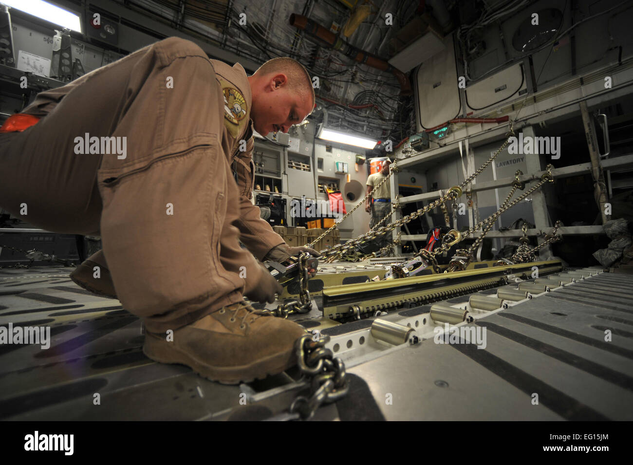 U.S. Air Force loadmaster Staff Sgt. Chris Rapp ties down chains to a ...