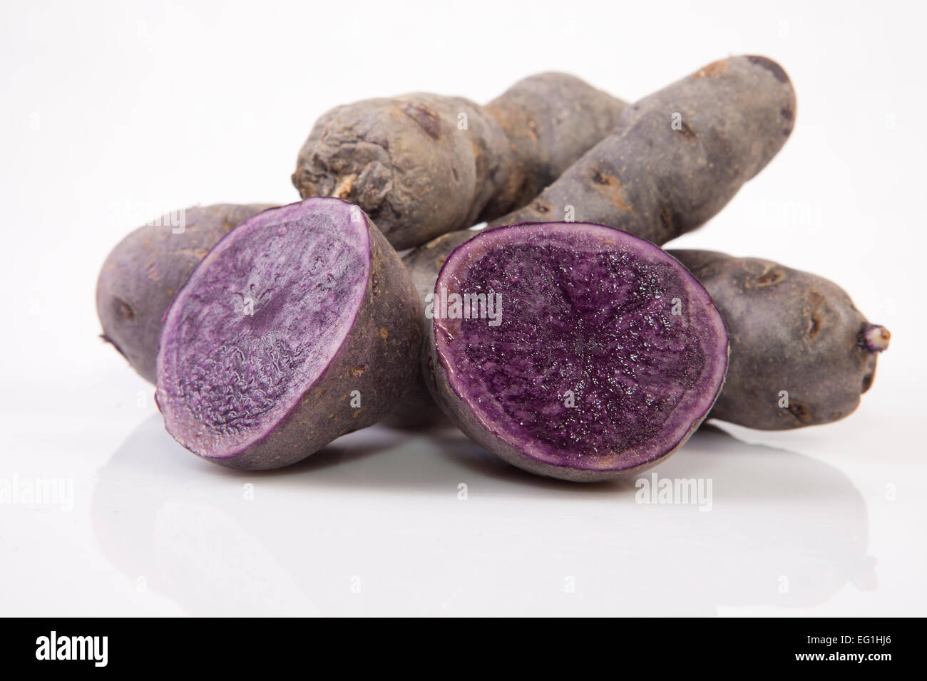 Sliced and whole purple Vitelotte potatoes. Isolated over white ...