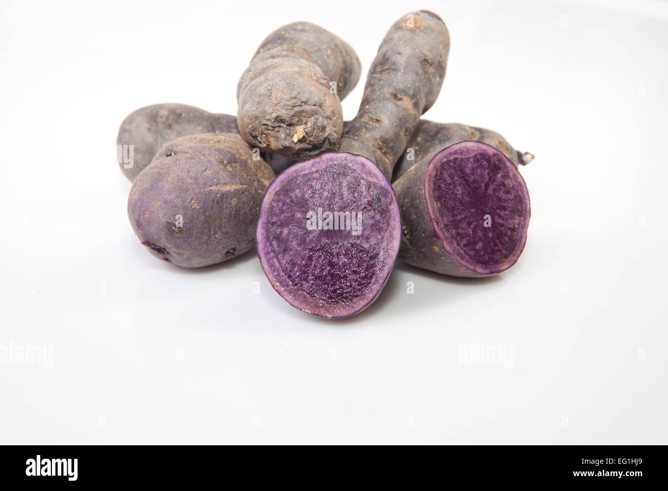 Sliced and whole purple Vitelotte potatoes. Isolated over white ...