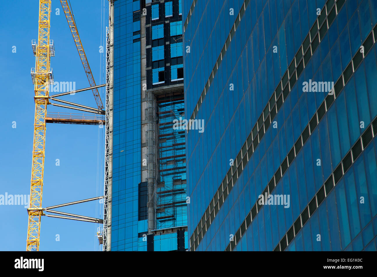 Huge crane rising near construction of a skyscraper against blue sky in ...