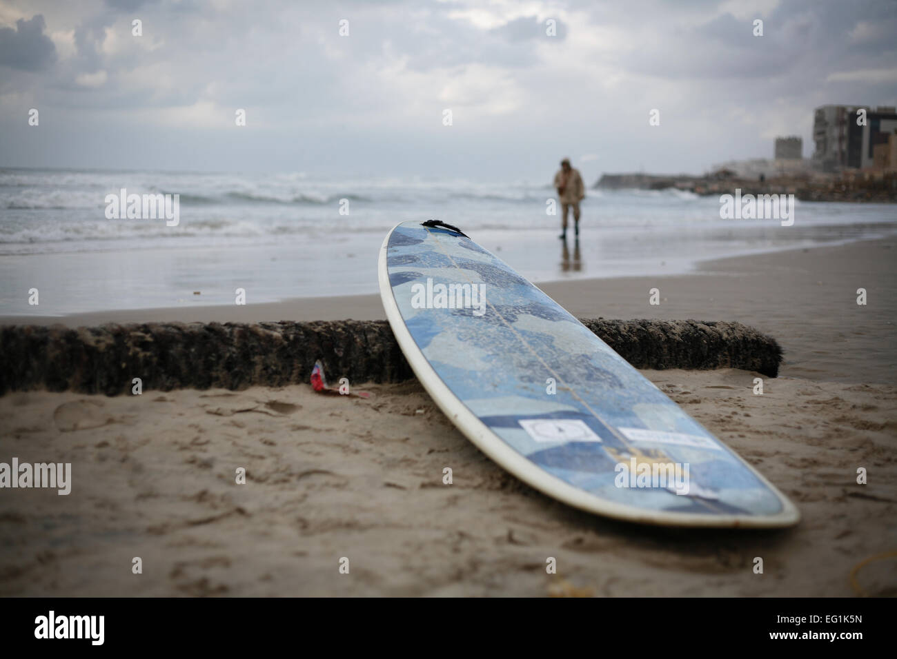 A Palestinian prepares his surfboard as he wades in the Mediterranean ...