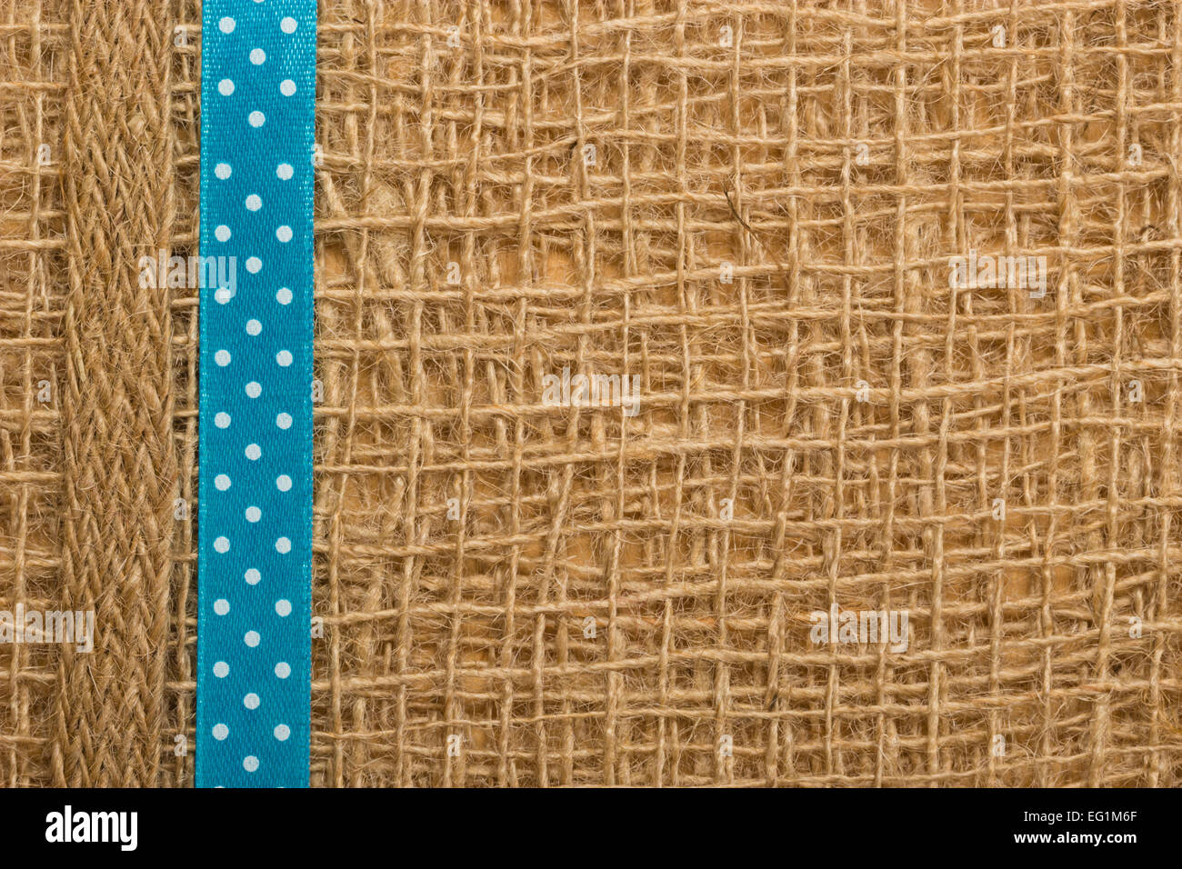 Polka dot blue ribbon on brown mesh material, natural burlap background ...