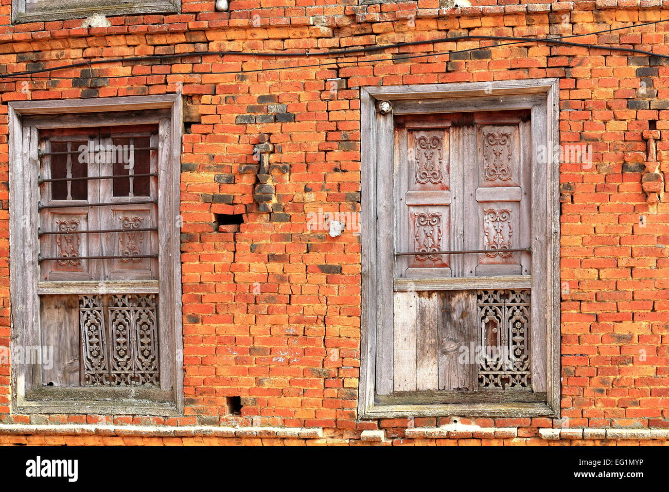 Paint-faded old carved wooden windows on the red brick facade of a ...