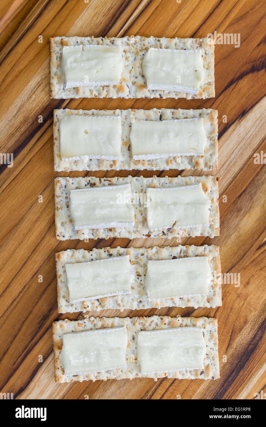 close up of slices of brie cheese on everything crackers on a wooden ...