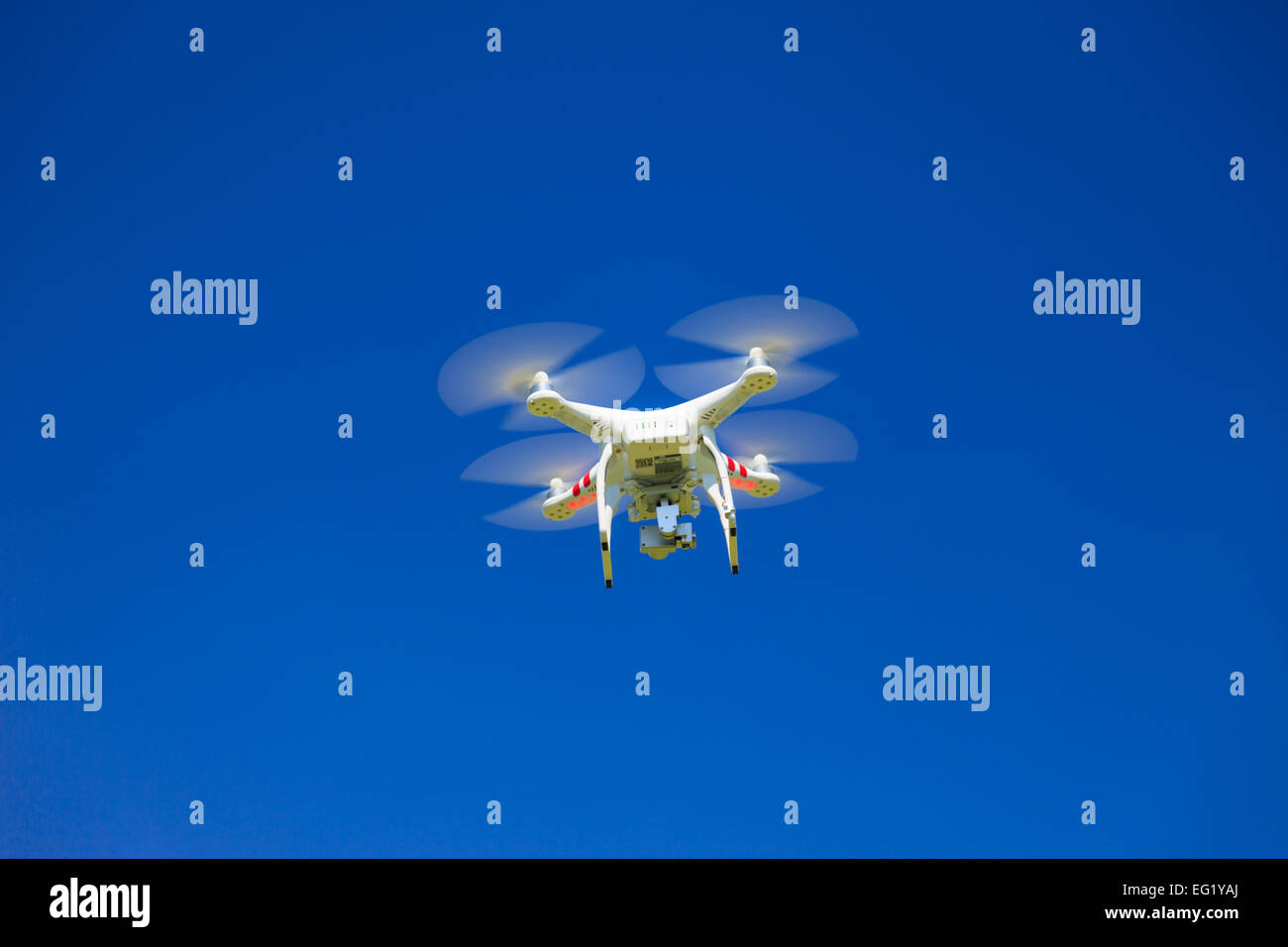 A view from below of a flying drone with a gimbal and camera attached ...