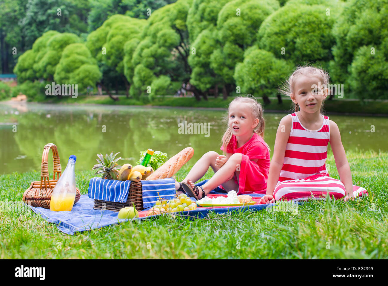 Adorable little girls picnicing in the park at sunny day Stock Photo ...